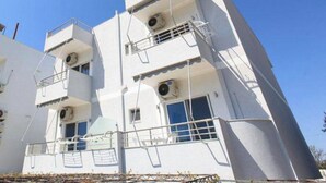 Um edifício de vários andares com varandas, aparelhos de ar condicionado e um céu azul límpido.