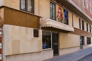 Um edifício com fachada plana, janelas amplas e uma varanda com toldo.