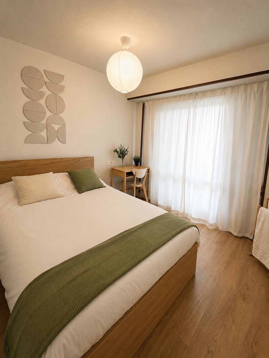 Quarto bem arrumado com cama, escrivaninha e janela com cortinas.
