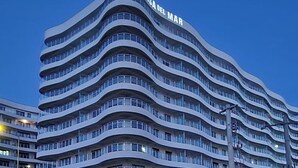 Um hotel moderno com fachada curva e várias varandas.