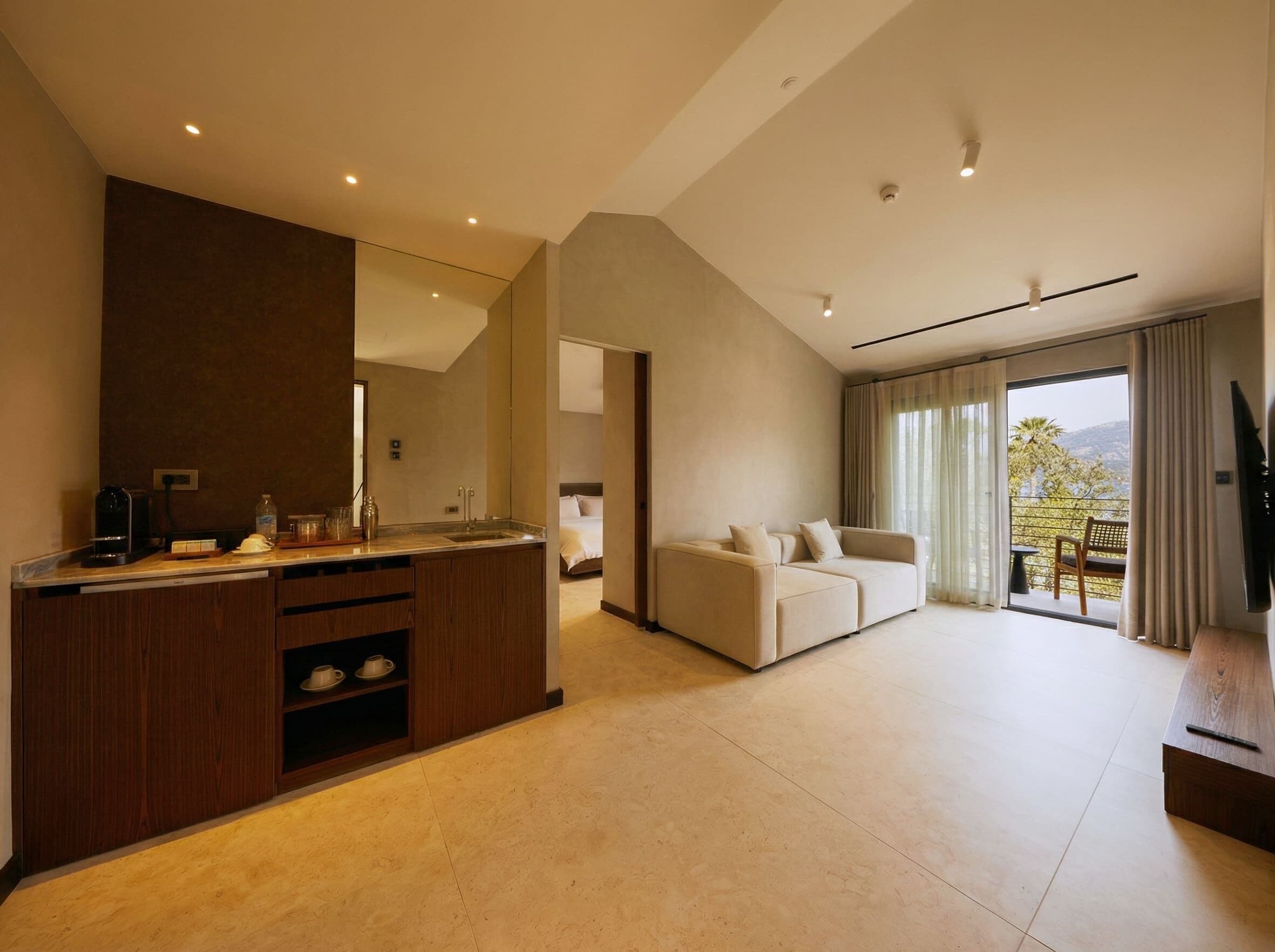Quarto de hotel moderno com cozinha, sofá, TV e varanda com vista.