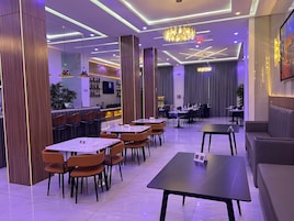 Um restaurante moderno com área de bar, várias mesas e cadeiras, e um candelabro.