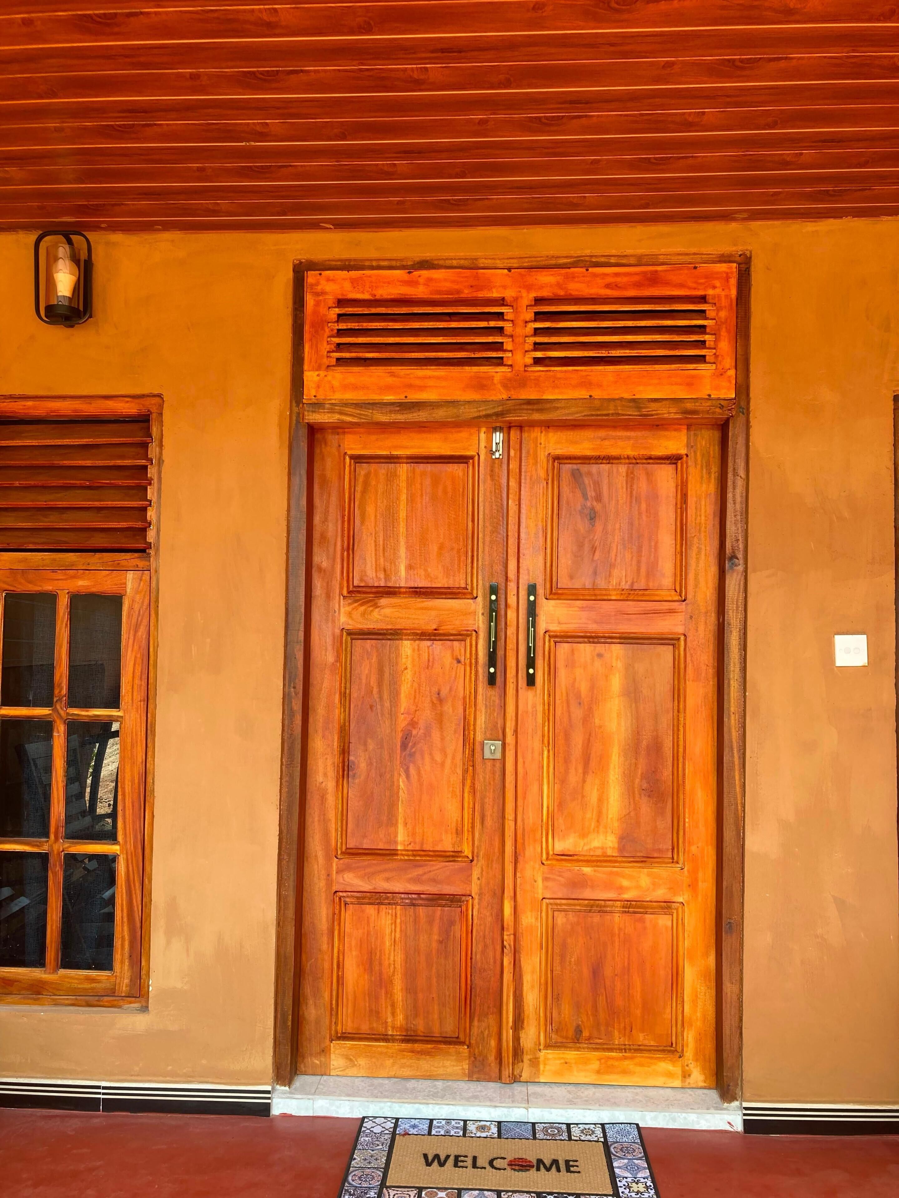 Uma porta dupla de madeira com um tapete de boas-vindas na frente.