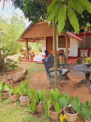 Uma casa com varanda coberta, plantas em vasos e móveis de exterior.