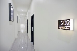 Corredor com placa indicando o número do quarto 202 e o nome 'Aljadid Pajus'.