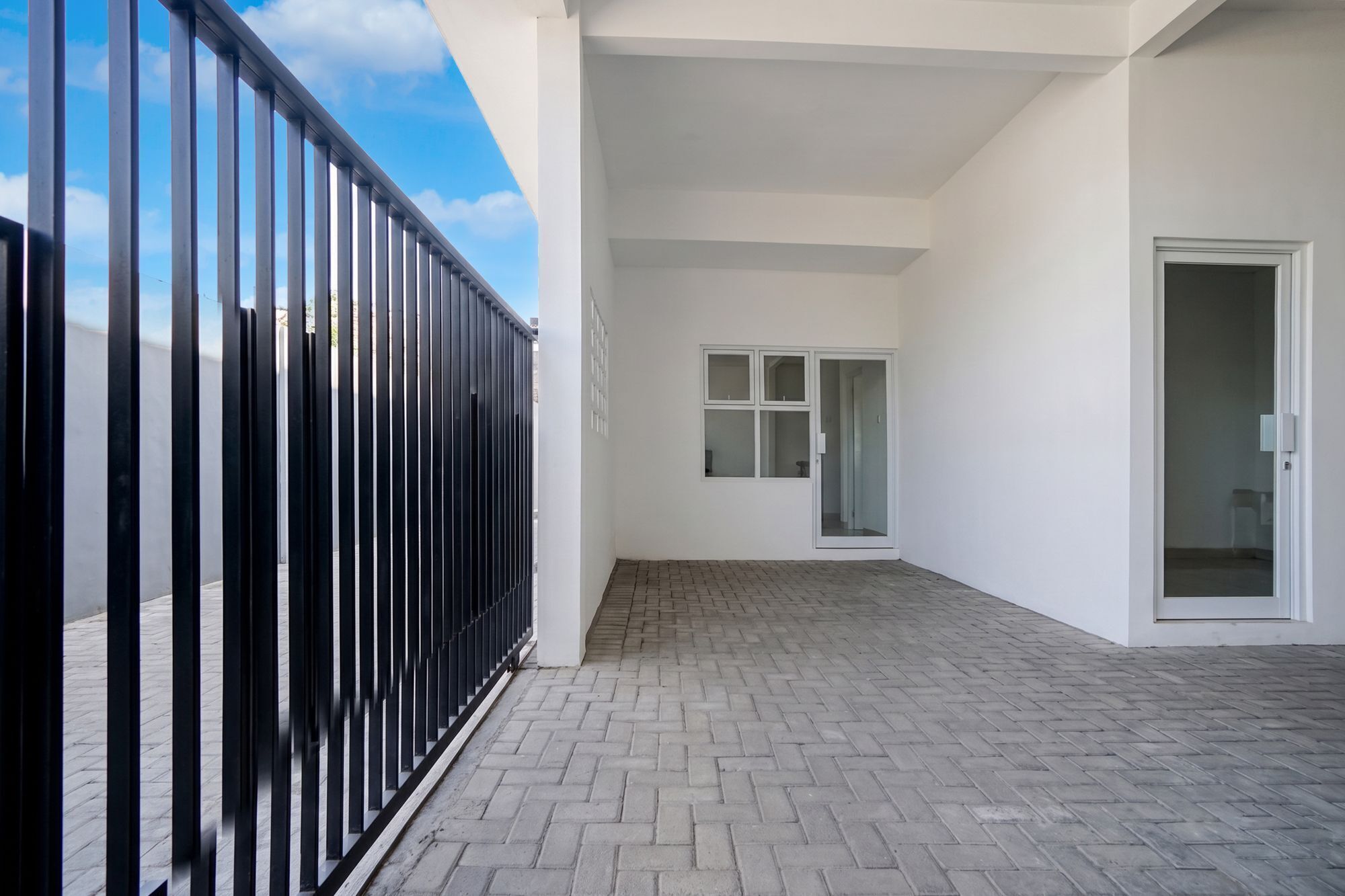 A corridor with a black metal fence, a door with a window, and a tiled floor.