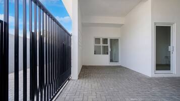 A corridor with a black metal fence, a door with a window, and a tiled floor.