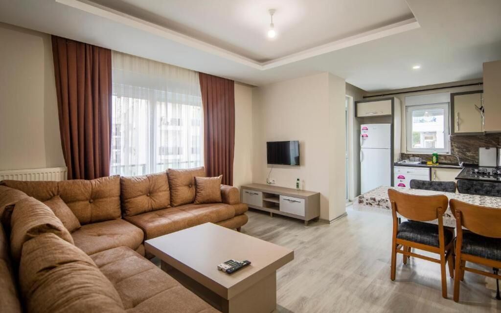 Uma sala de estar com sofá, mesa de centro, televisão e um espaço de jantar com cadeiras.