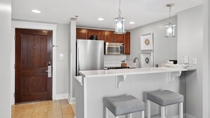 Uma cozinha moderna com ilha central, eletrodomésticos de aço inoxidável e iluminação pendente.