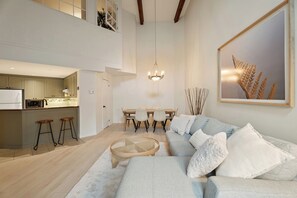 Um espaço de estar moderno com área de jantar, sofá, mesa de centro e cozinha.
