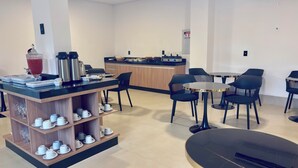 Um saguão moderno de hotel com um espaço para café, área de estar e um balcão.