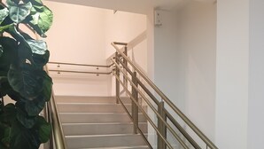 Uma escadaria com corrimão, um vaso de planta e um tapete de entrada com a inscrição 'HOTEL & CELEIRO'.