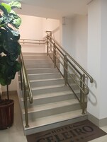 Uma escadaria com corrimão, um vaso de planta e um tapete de entrada com a inscrição 'HOTEL & CELEIRO'.
