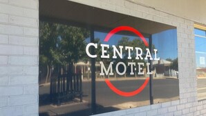 Placa de motel com o nome 'CENTRAL MOTEL' e uma vista parcial da área ao redor.