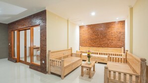 Quarto com sofá de madeira, mesa de centro de madeira e parede decorativa em tijolo.