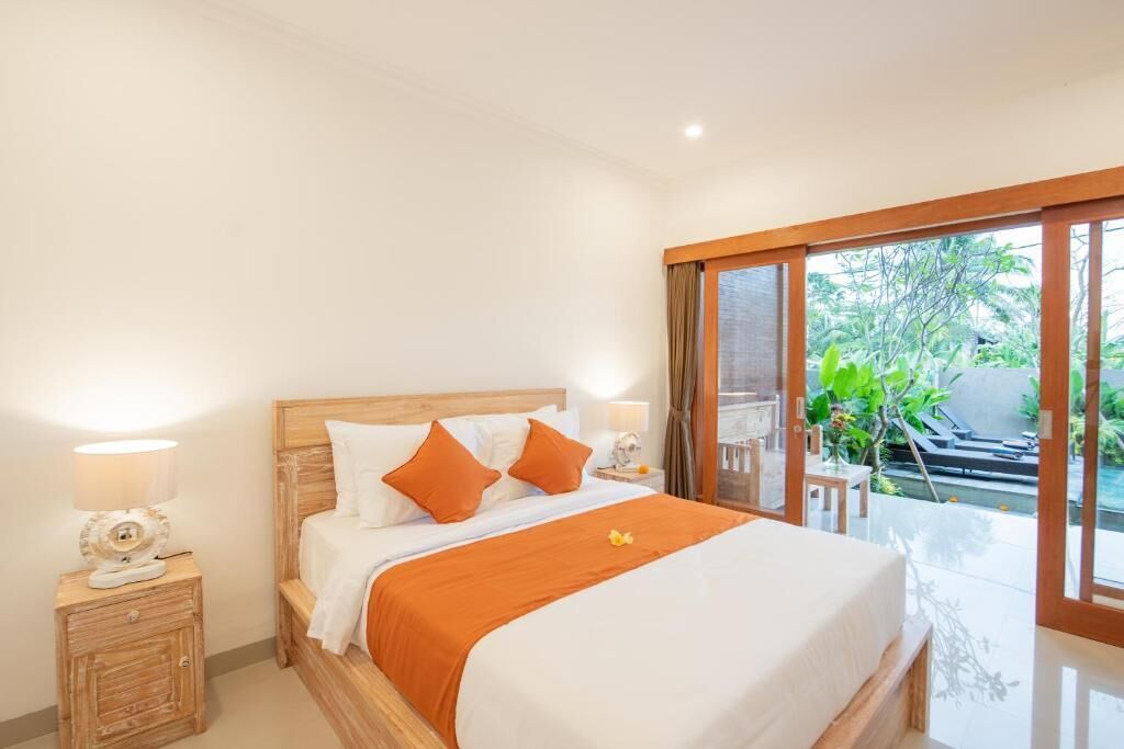 Quarto de hotel com cama, mesas de cabeceira, janela e vista para área verde.