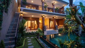 Uma casa de dois andares com varanda, piscina e um jardim bem cuidado.