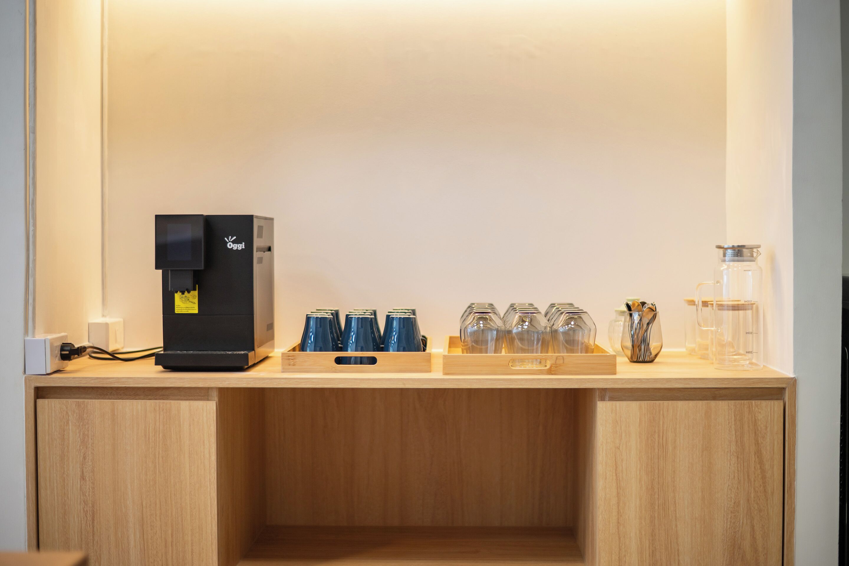 Um espaço com café, máquina de café, chávenas, copos e um frasco.