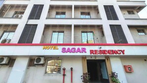 Um edifício de vários andares com uma placa indicando 'HOTEL SAGAR RESIDENCY'.