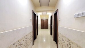 Um corredor com piso ladrilhado, paredes padronizadas e portas de madeira.