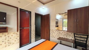 Quarto com cama, escrivaninha, cadeira, televisão e guarda-roupa.