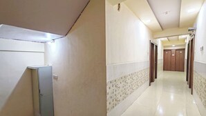 Um corredor com geladeira, escada e um lance que leva a uma porta.