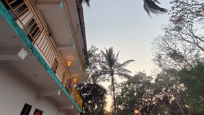 Um edifício de vários andares com varandas, céu claro e árvores ao redor.
