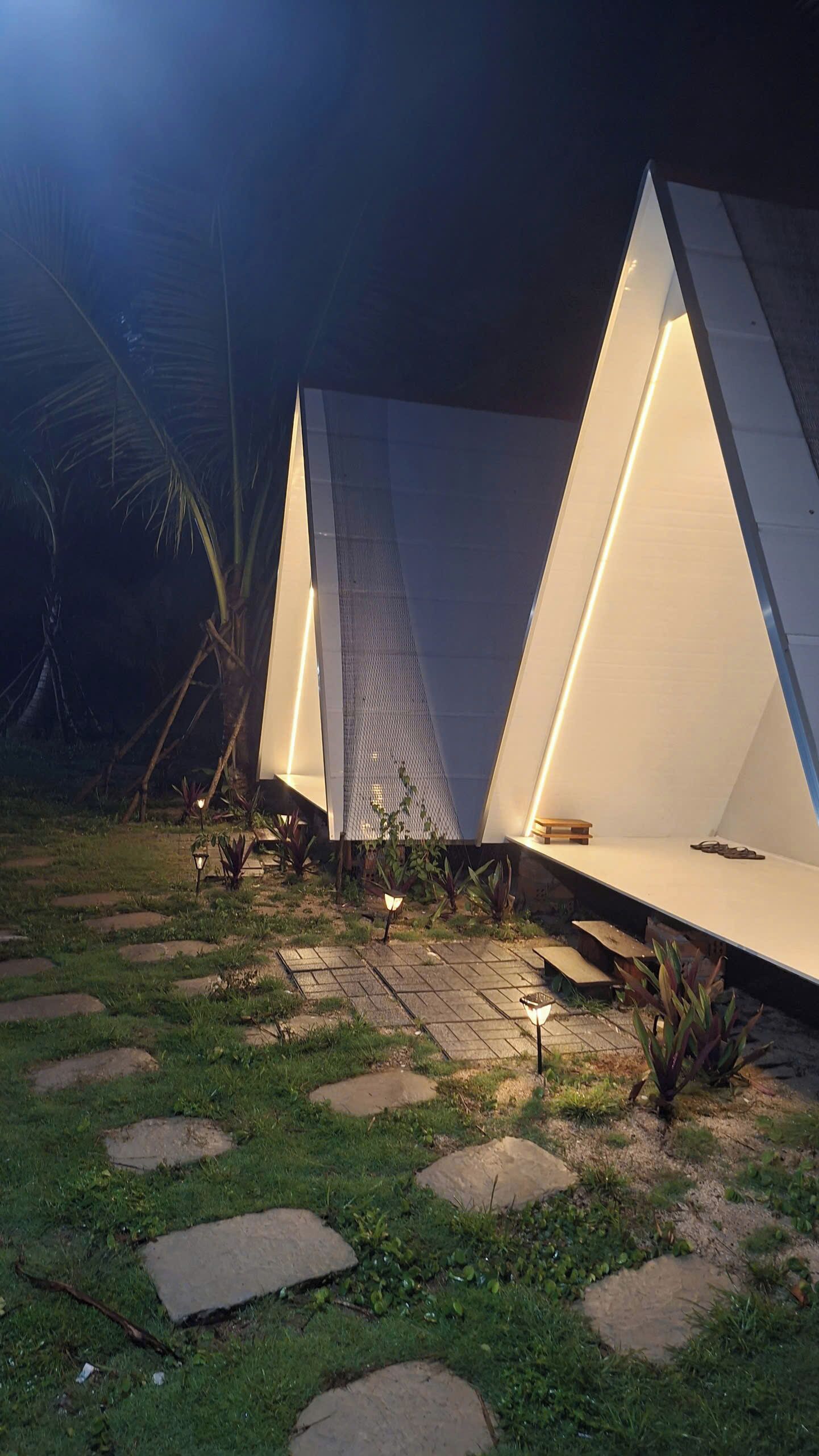 Um edifício moderno com fachada triangular e um caminho pavimentado que leva até ele.