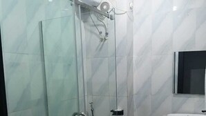 Um banheiro moderno com chuveiro em box de vidro, vaso sanitário, pia e espelho.