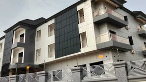 Um edifício residencial com vários andares, varandas, portão fechado e design arquitetônico moderno.