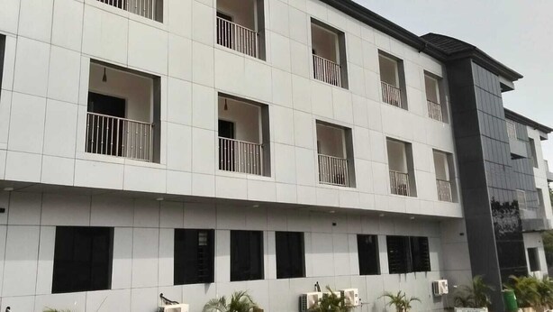 Um edifício com vários andares, fachada branca, varandas e aparelhos de ar condicionado.