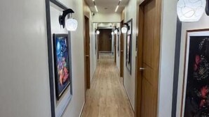 Um corredor de hotel com piso de madeira, obras de arte emolduradas nas paredes e iluminação embutida.