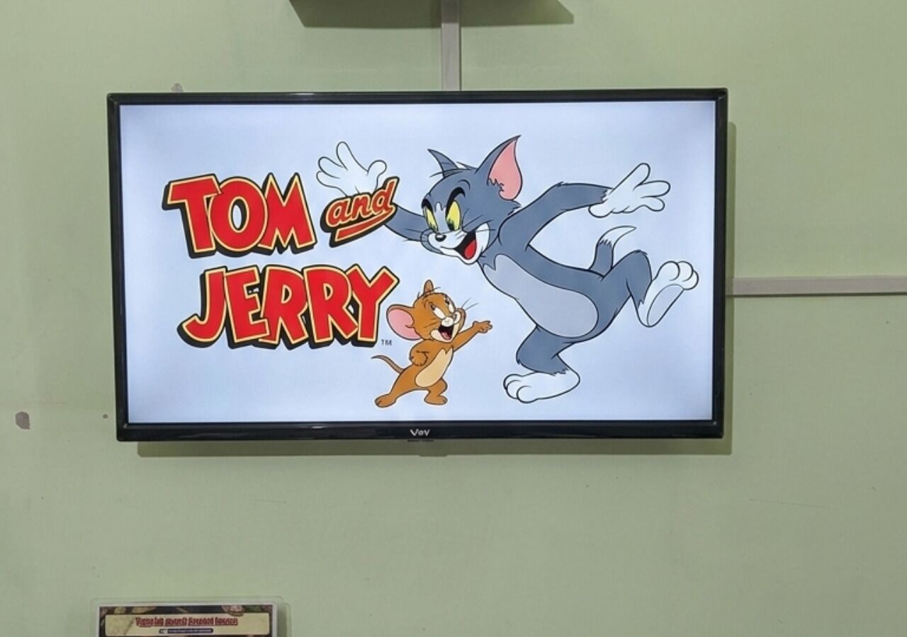 Uma tela de televisão exibindo o título 'Tom e Jerry' com os personagens Tom e Jerry.