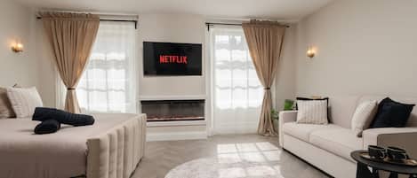 Uma sala de estar moderna com lareira, sofá, cama e televisão na parede.