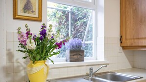 Uma cozinha com uma janela, um vaso amarelo com flores, e uma placa com a inscrição 'Flowerpot'.