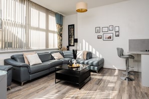 Uma sala de estar moderna com um sofá seccional, uma mesa de centro de vidro e um espaço para bar.