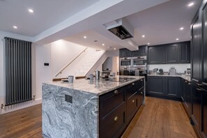 Cozinha moderna com armários escuros, ilha de mármore e forno embutido.
