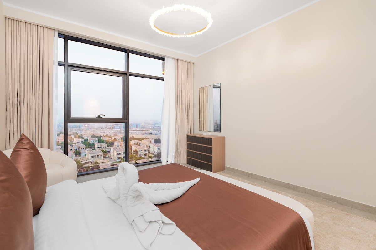 Quarto de hotel com cama grande, penteadeira, espelho e vista para a cidade através de uma janela ampla.