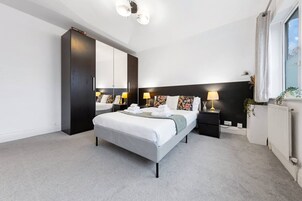 Quarto moderno com uma cama grande, mesas de cabeceira, guarda-roupa e uma janela com vista.
