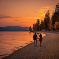 Um casal caminhando numa praia de pedras com o pôr do sol ao fundo.