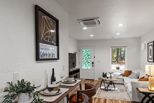 Uma sala de estar moderna com área de jantar, sofá, mesa de centro e televisão.