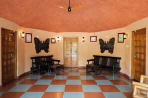Quarto com duas portas de madeira, soalho xadrez e duas bancadas.