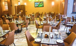 Um restaurante com várias mesas e cadeiras, cada conjunto com pratos, talheres e guardanapos.