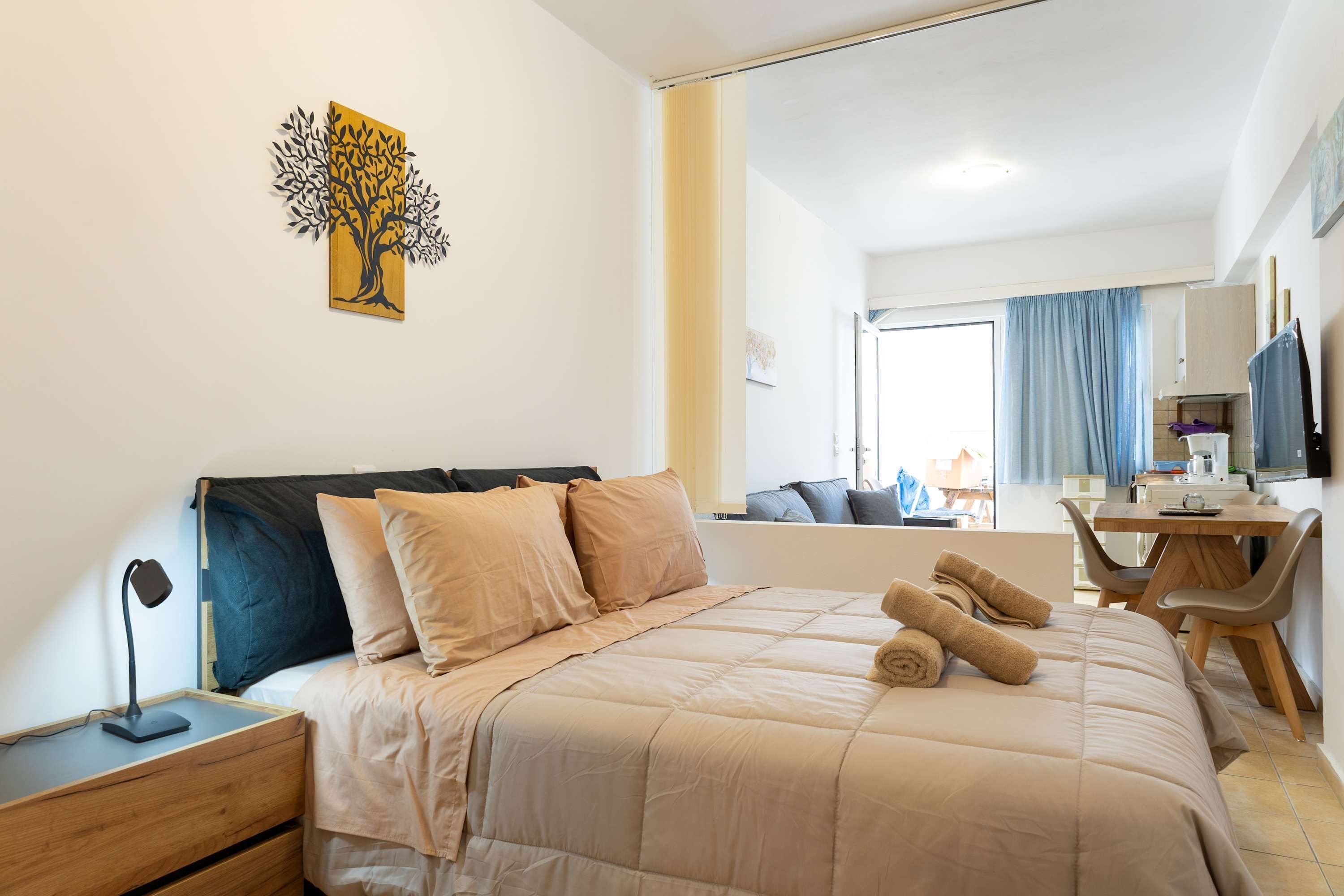 Quarto de hotel com uma cama, uma escrivaninha, uma cadeira, uma mesa de cabeceira, um abajur e um quadro na parede.