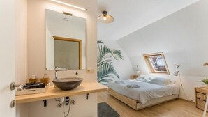Quarto moderno com cama de madeira, um espelho grande, mesa de cabeceira de madeira e um claraboia.