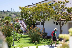 Hotel com um jardim bem cuidado, escadaria que leva à entrada e vista ampla da paisagem ao redor.