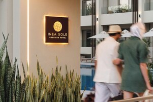 Placa do Hotel Boutique INEA SOLE com design moderno e área de piscina ao fundo.