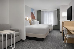 Quarto de hotel com cama, duas mesas de cabeceira, escrivaninha, cadeira, televisão e um quadro na parede.