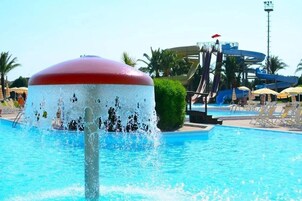 Piscina com fonte, rodeada por espreguiçadeiras e guarda-sóis.