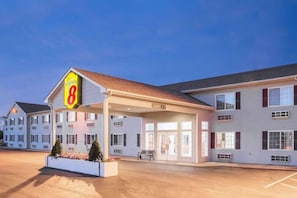 Um motel com um grande letreiro 'Super 8', área de estacionamento coberta e uma fileira de quartos com janelas.